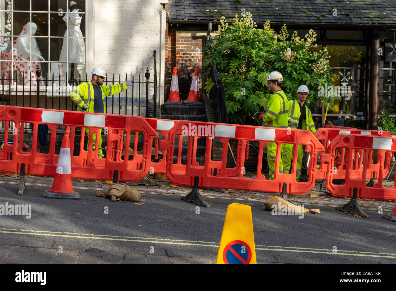 Three Builders in high visibility clothing behind a barrier in the road ...