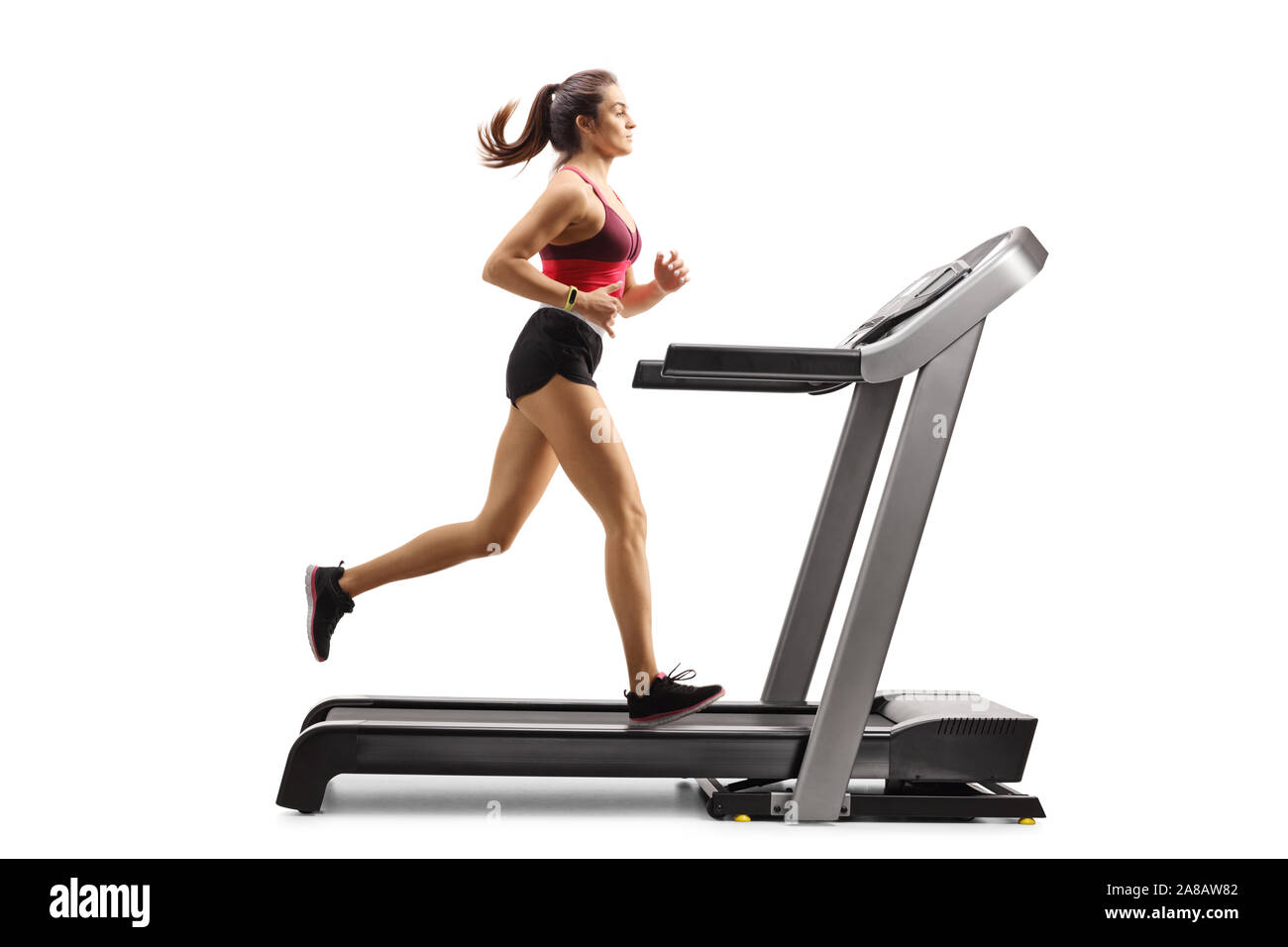 Full length profile shot of a young woman exercising on a treadmill ...