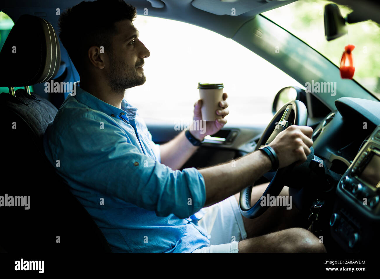 transportation and vehicle concept - man drinking coffee while driving ...