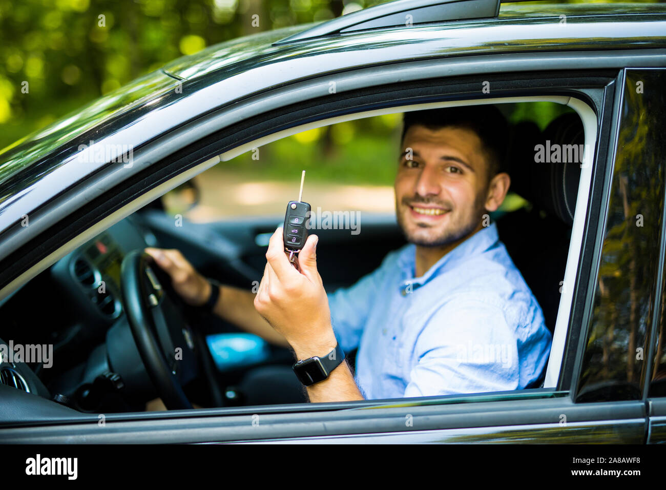 Young man sitting inside new car with keys. Smiling Stock Photo - Alamy