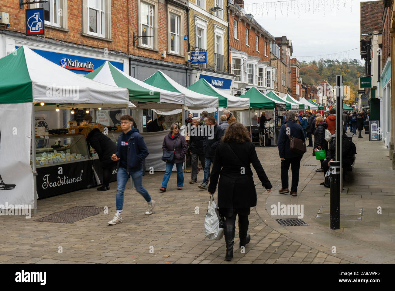 Shopper walking through a busy high street next to market stalls Stock ...
