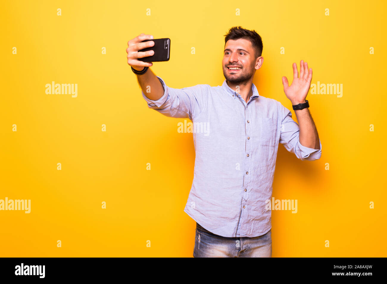 Young man in casual outfit taking picture of himself, using smart phone ...