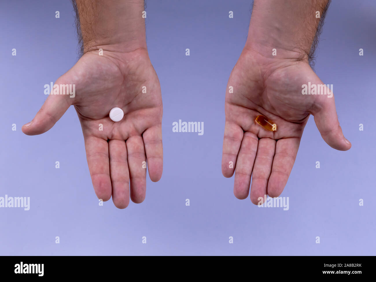 Man hands giving two big pills. White and orange. Make your selection ...