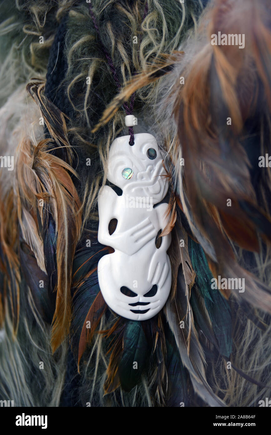 A traditional Maori bone carving nestled in a feather cloak, New ...