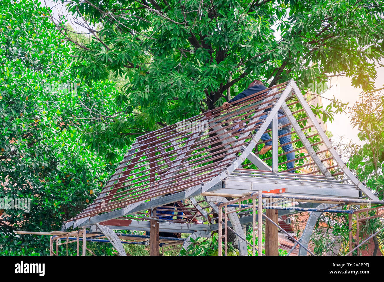 Welder and painter are helping to build a gable roof structure below a ...
