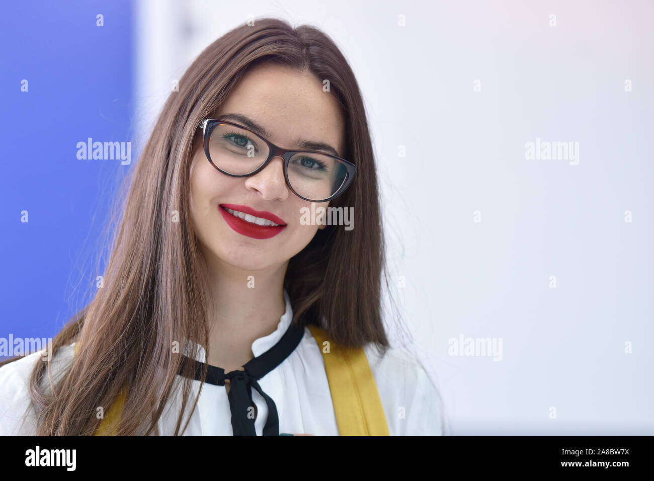 Beautiful female student wearing glasses standing at university campus ...