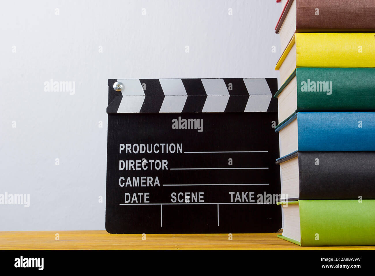 A stack of books with multi-colored binders and a movie clapper on a ...