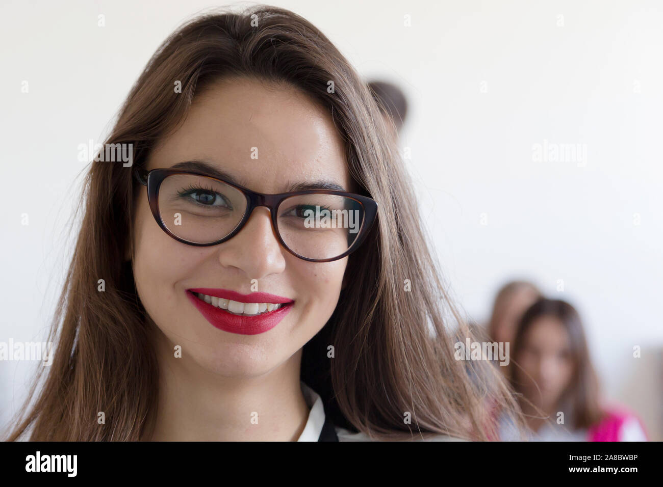 Beautiful female student wearing glasses standing at university campus ...