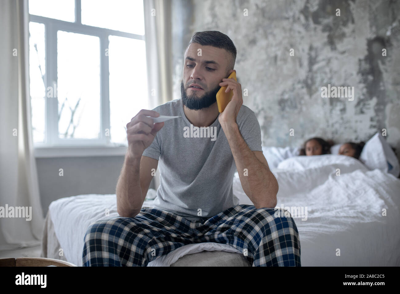 Father calling doctor after measuring temperature of daughters Stock ...