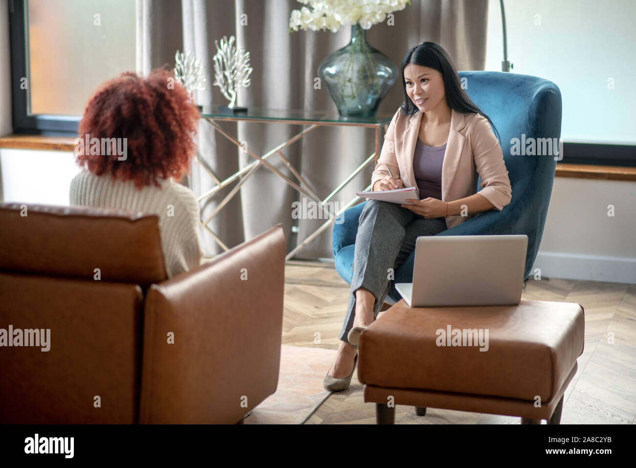 Dark-haired psychoanalyst sitting in armchair in front of patient Stock ...