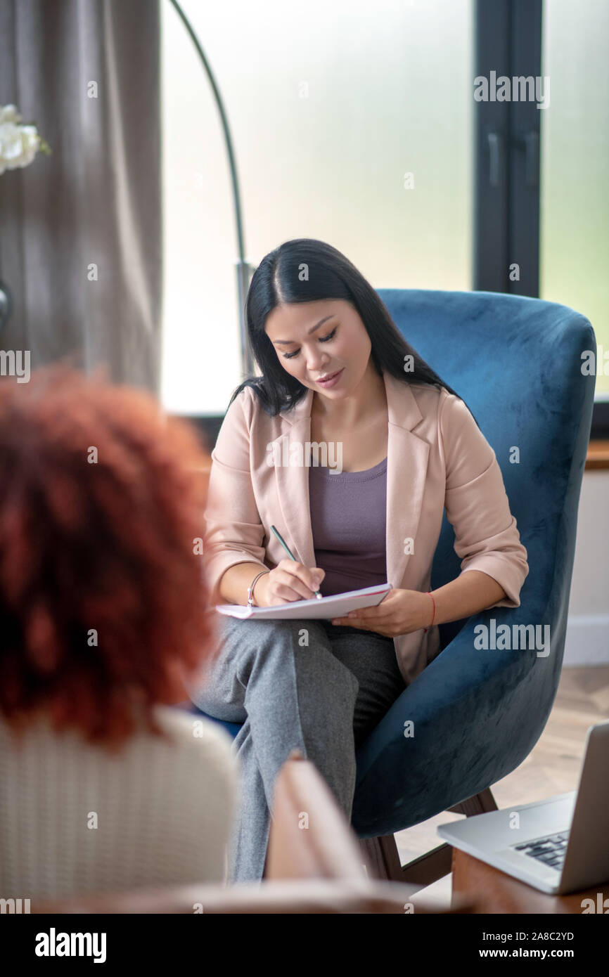 Psychoanalyst making notes while listening to client Stock Photo - Alamy