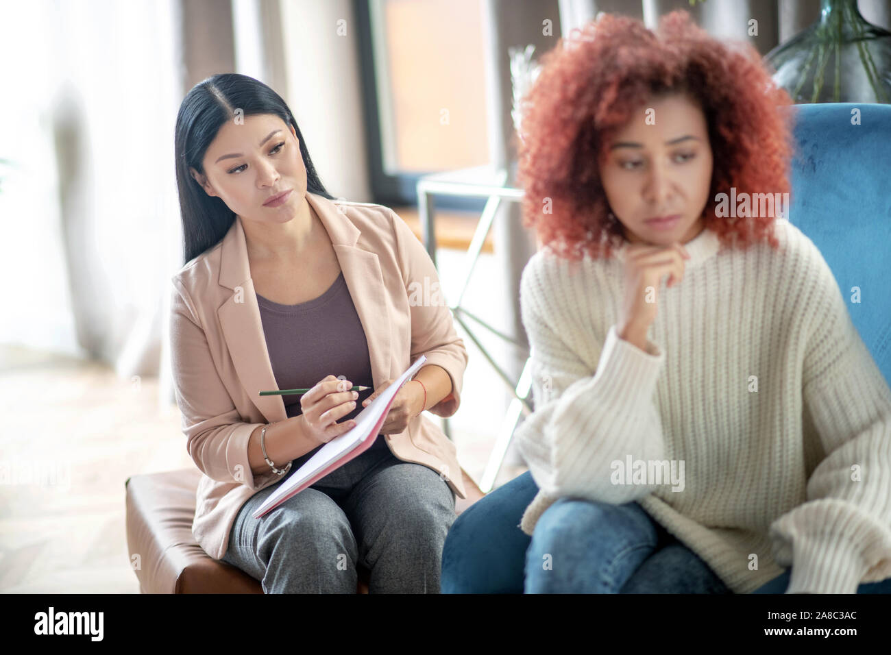 Dark-haired mature psychologist listening to depressed client Stock ...