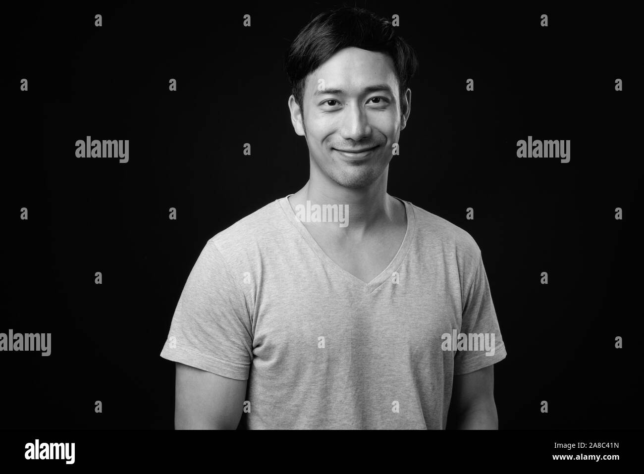 Young handsome Asian man against black background Stock Photo - Alamy