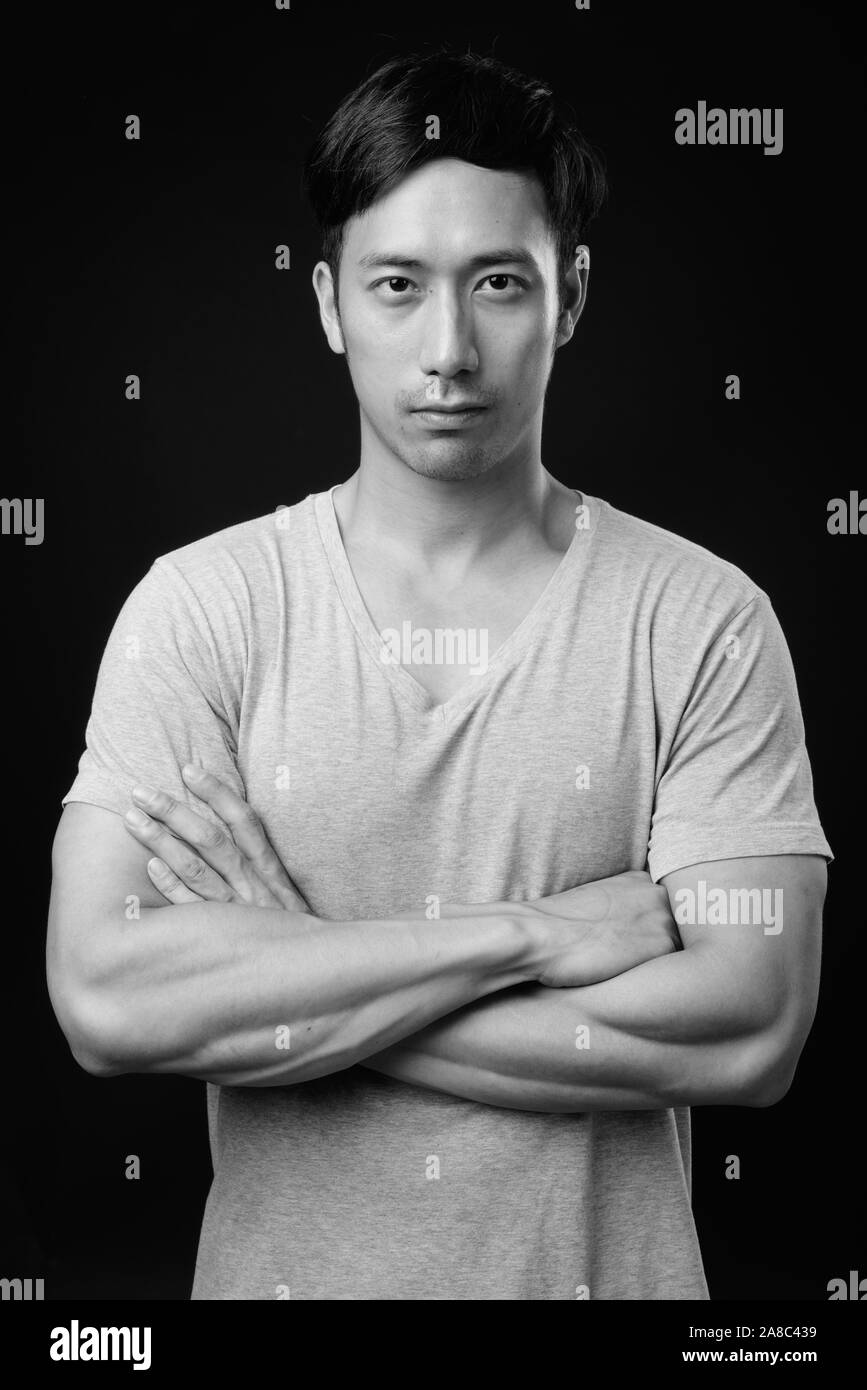 Young handsome Asian man against black background Stock Photo - Alamy