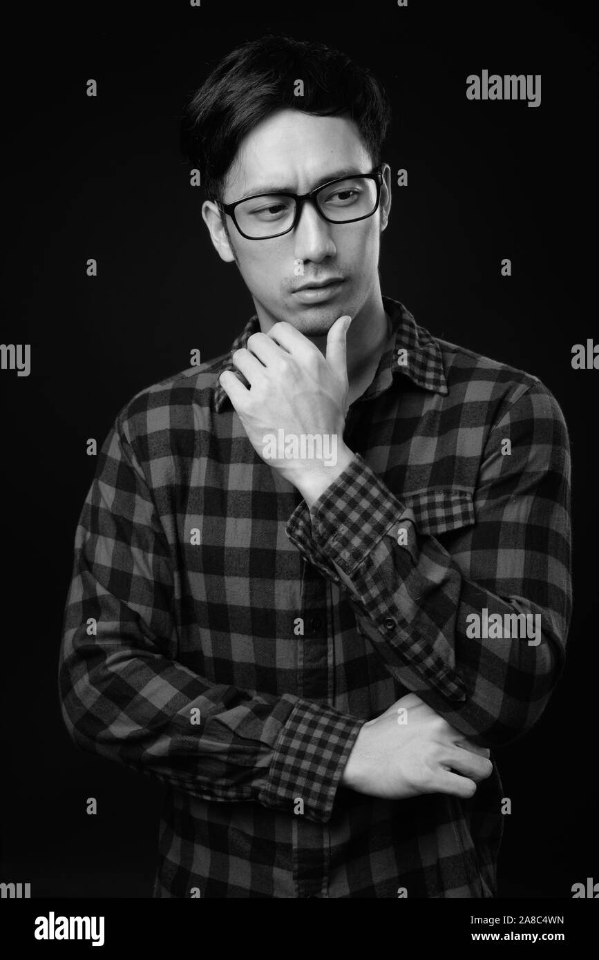 Young handsome Asian man against black background Stock Photo - Alamy