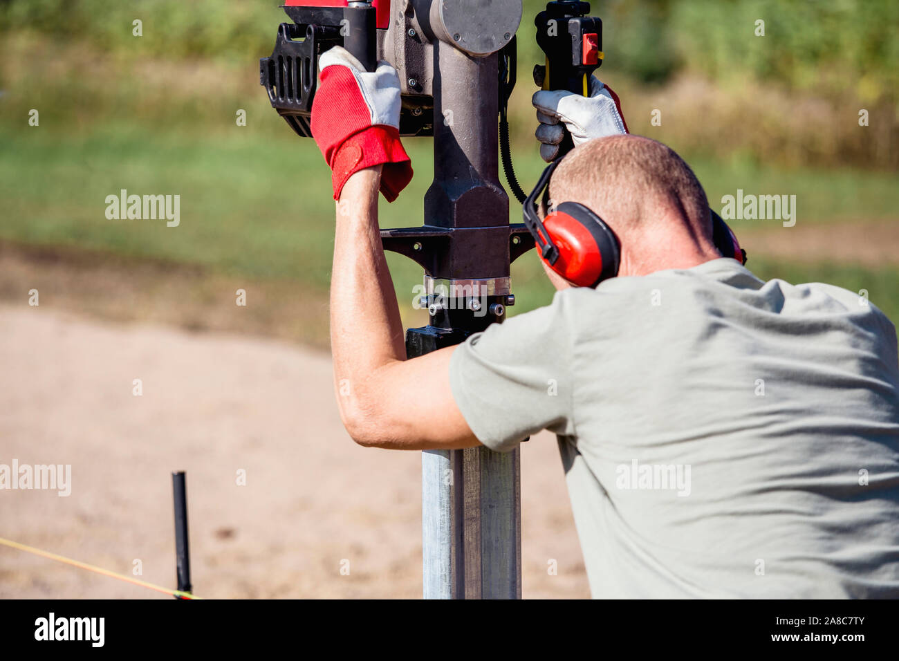 Man using gasoline hand held pole ramming tool outdoors on construction ...