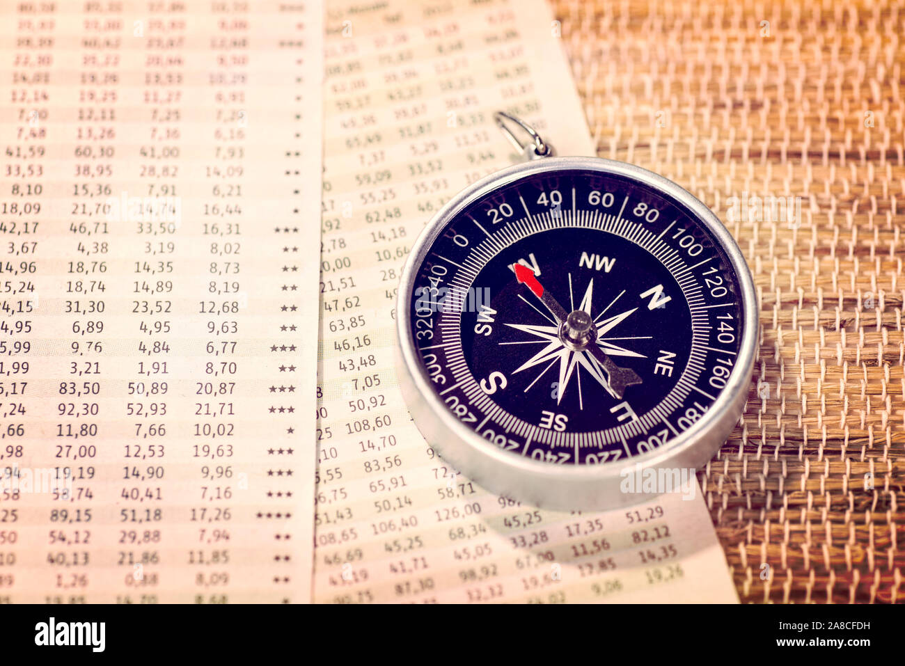 Stock market tables and a compass for orientation Stock Photo - Alamy