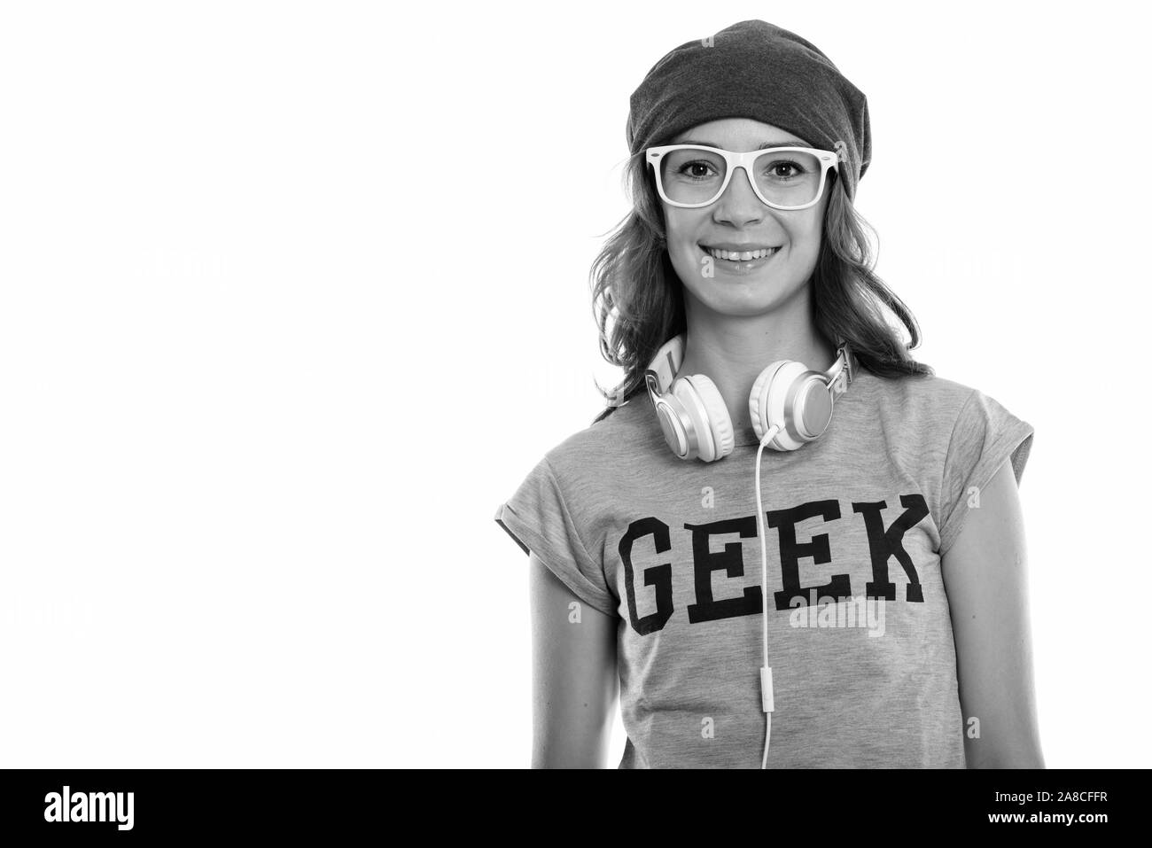 Studio shot of happy geek girl smiling and wearing eyeglasses with headphones around neck Stock ...