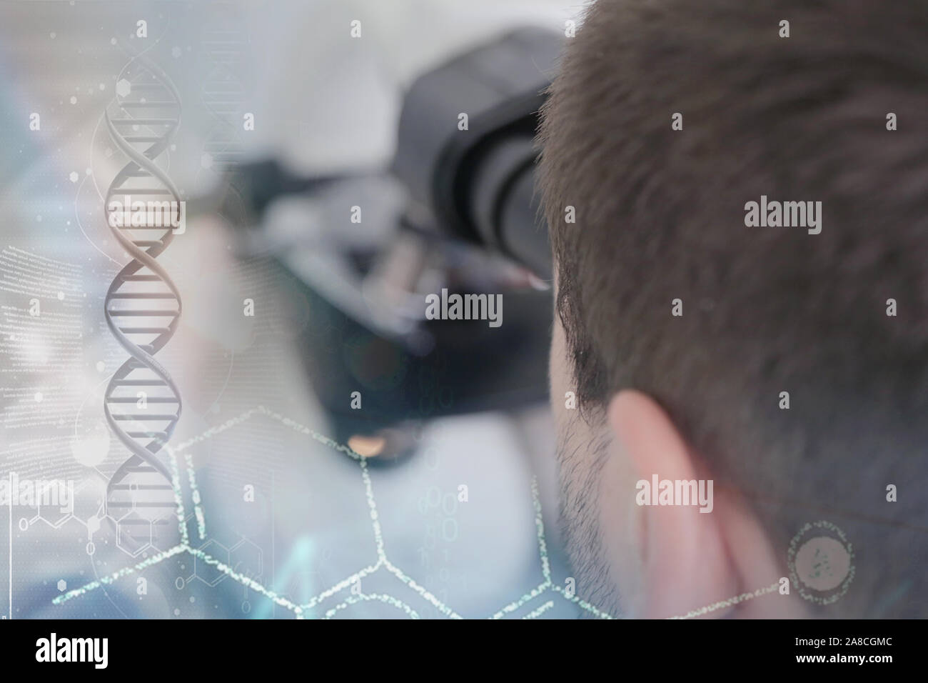 Young male male scientist looking through a microscope in a laboratory ...