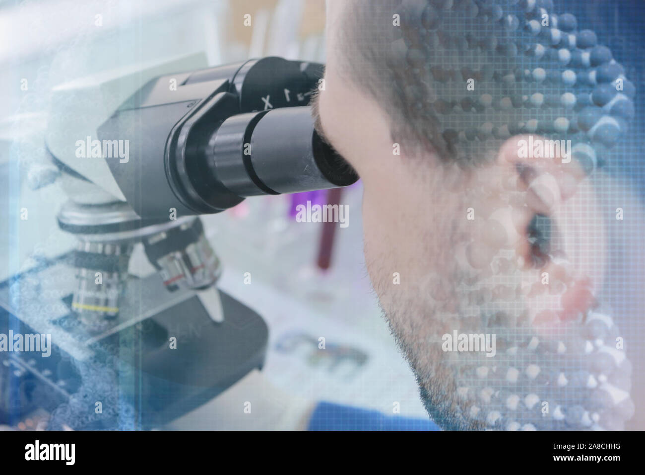 Young male male scientist looking through a microscope in a laboratory ...
