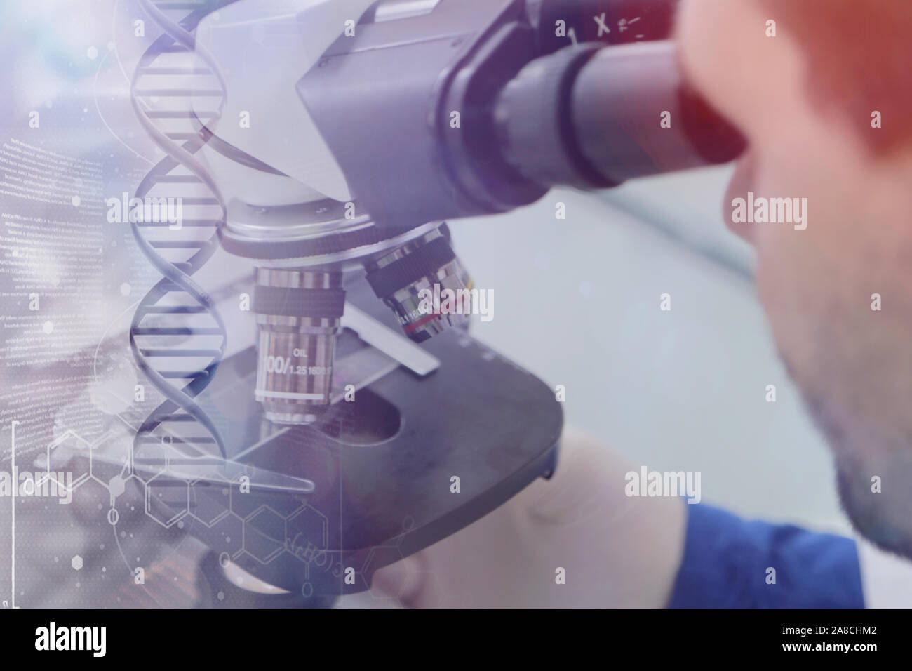 Young male male scientist looking through a microscope in a laboratory ...