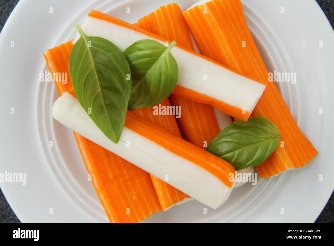 six fresh surimi with a leaf of basil on a plate Stock Photo - Alamy