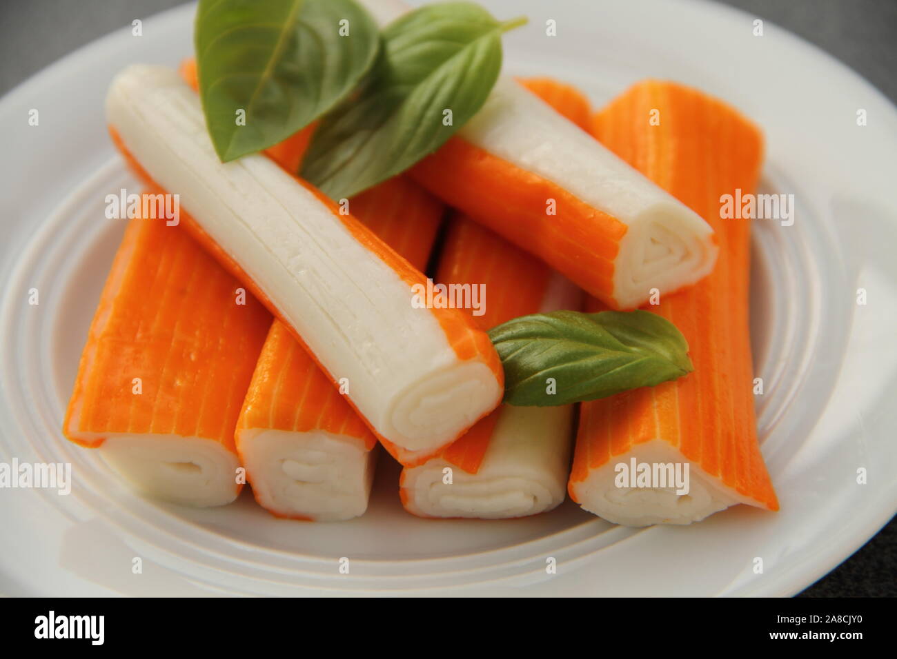 six fresh surimi with a leaf of basil on a plate Stock Photo - Alamy