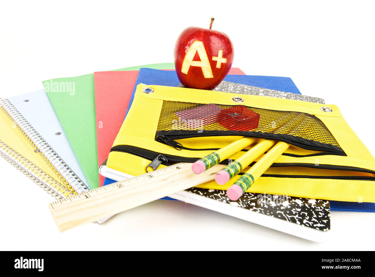 A plus grade carved into a red apple sitting on notebooks and school ...