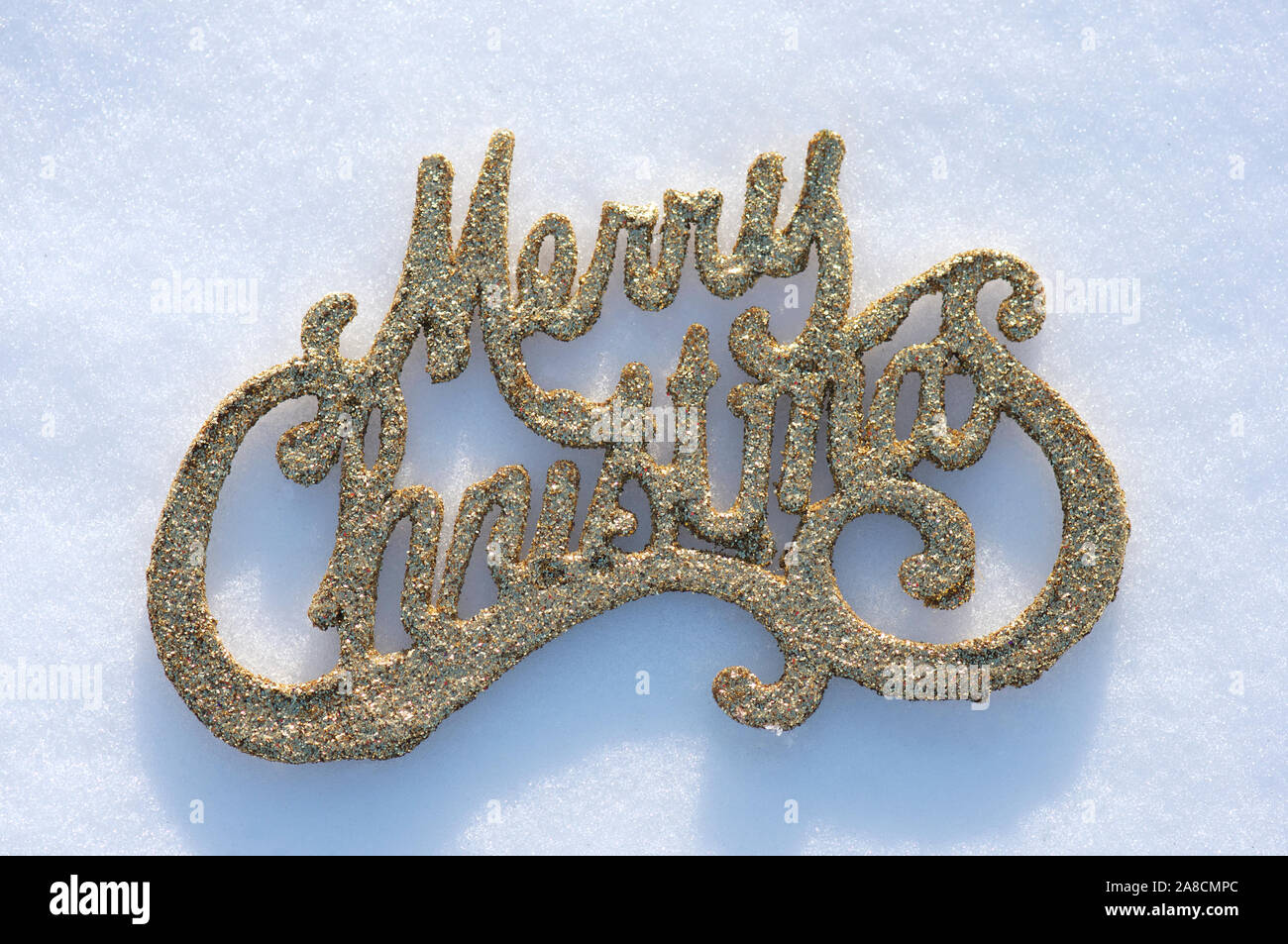 Merry Christmas greeting message in gold glitter on fresh white powder ...