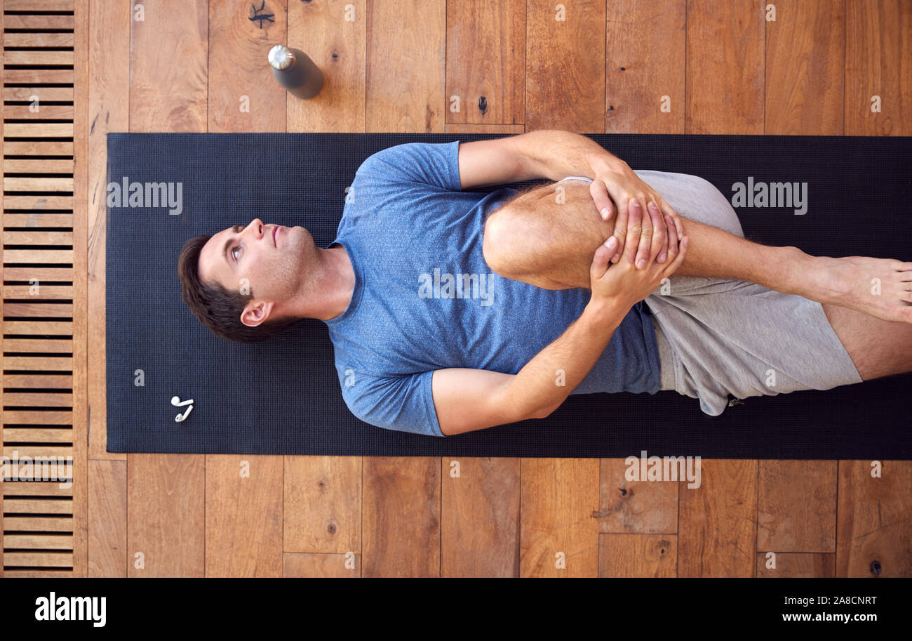 Overhead View Of Man Lying On Exercise Mat On Wooden Floor Stock Photo ...