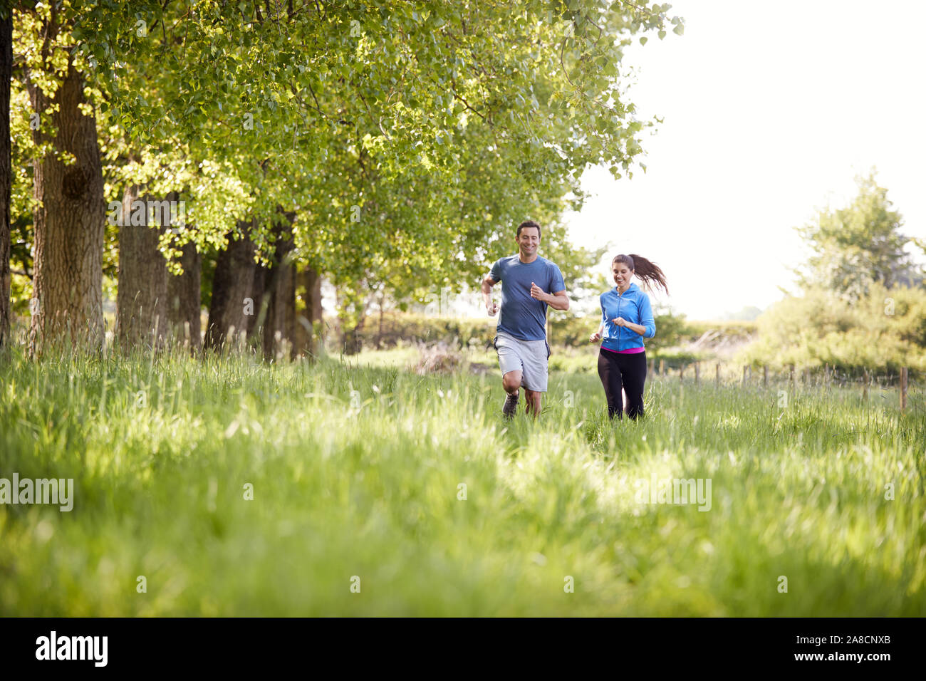 Couple Exercising Running Through Countryside Field Together Stock ...