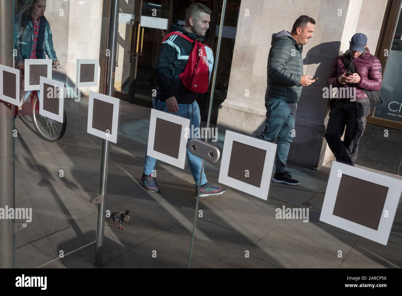 Londoners and squares on the glass screens at a bus stop in Kingston ...