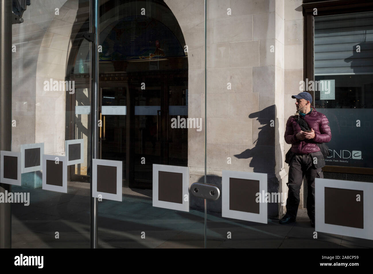 A Londoner and squares on the glass screens at a bus stop in Kingston ...