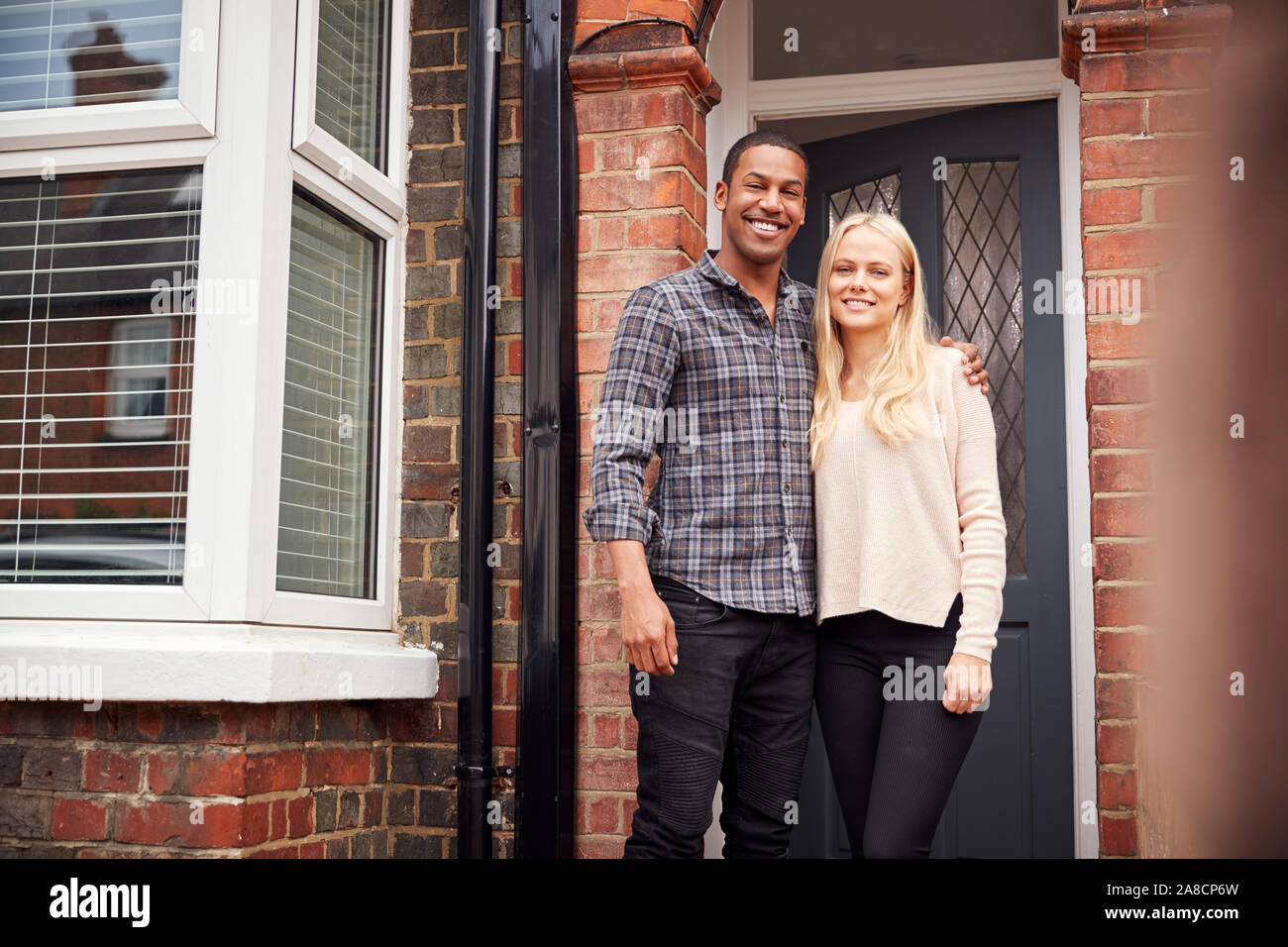 Portrait Of Proud Young Couple Standing Outside First Home Together ...