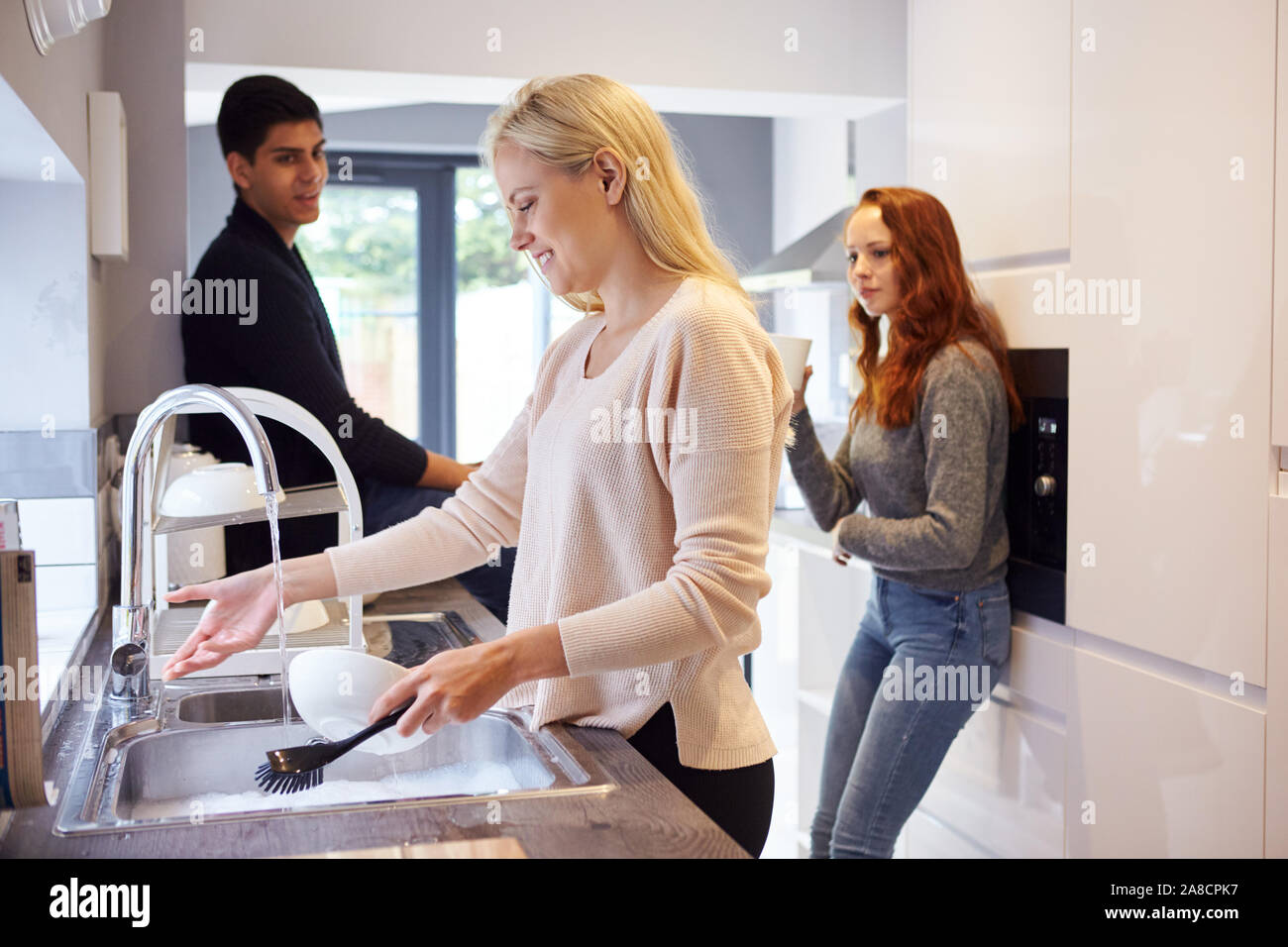 Group Of College Student Friends In Shared House Kitchen Washing Up And ...