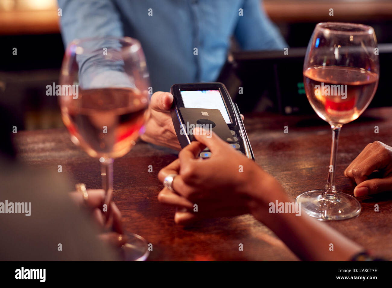 Close Up Of Woman Paying For Drinks At Bar After Work Using Contactless ...