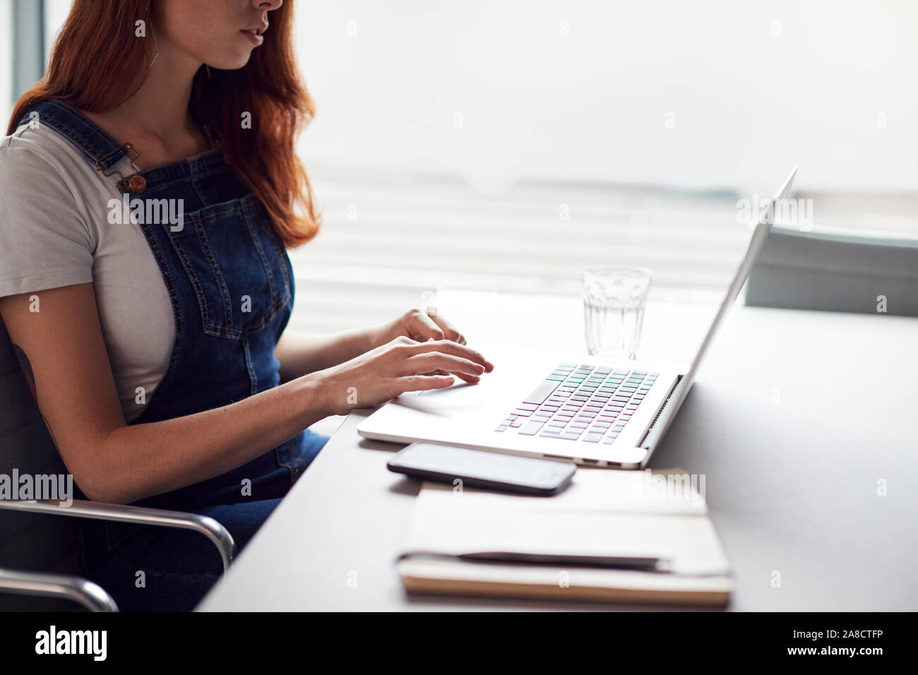 Close Up Of Casually Dressed Young Businesswoman Working On Laptop At ...