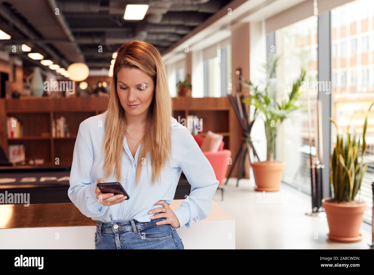 Casually Dressed Young Businesswoman Checking Mobile Phone In Modern ...