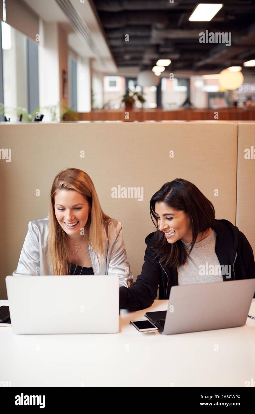 Two Young Businesswomen In Meeting Around Table In Modern Open Plan ...
