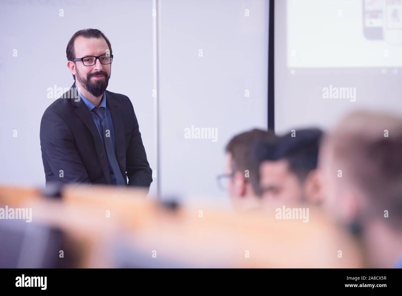 Group of students study with professor in modern school classroom. Male ...