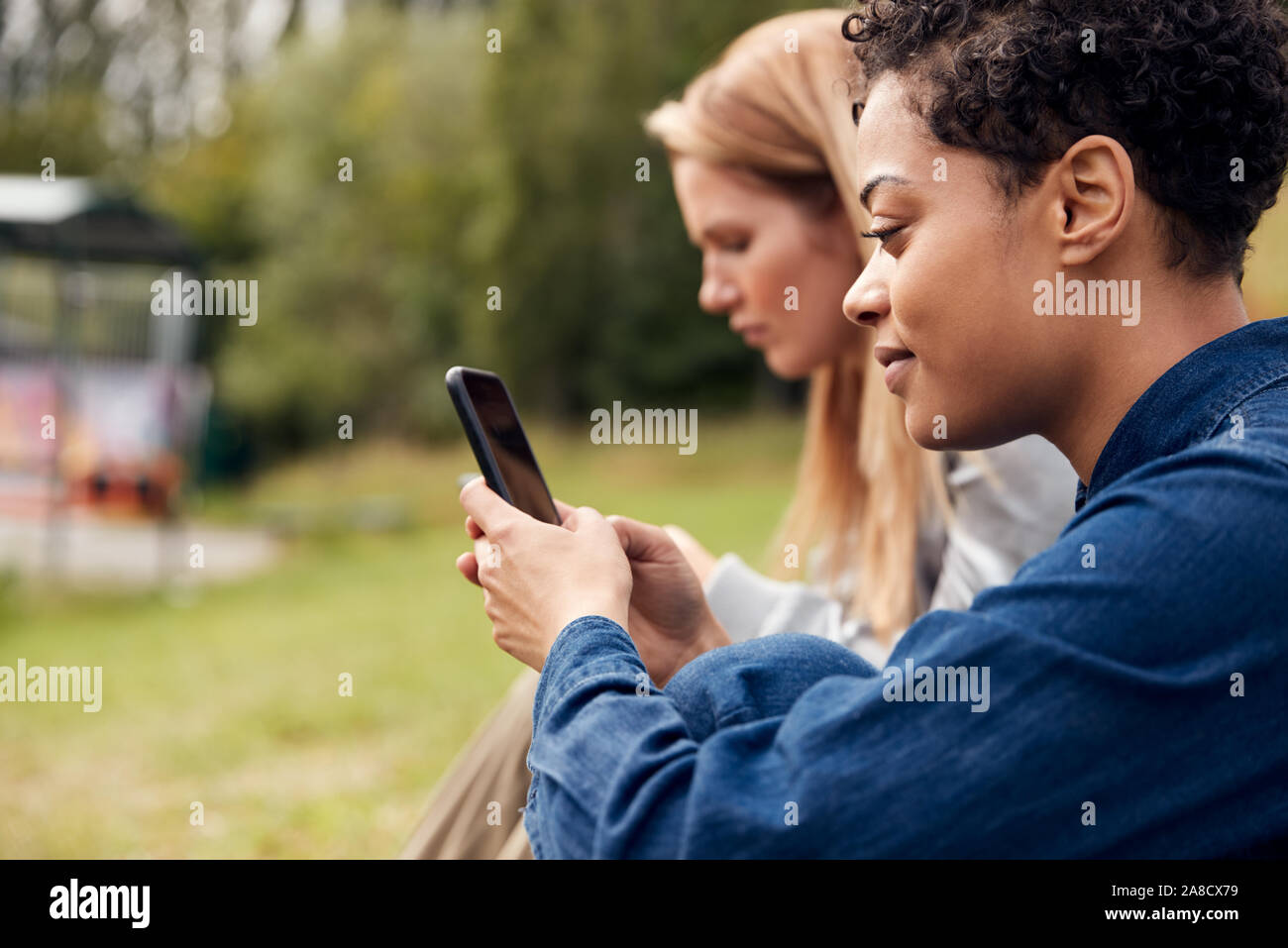 Female Friends Using Mobile Phones In Urban Skate Park Stock Photo - Alamy