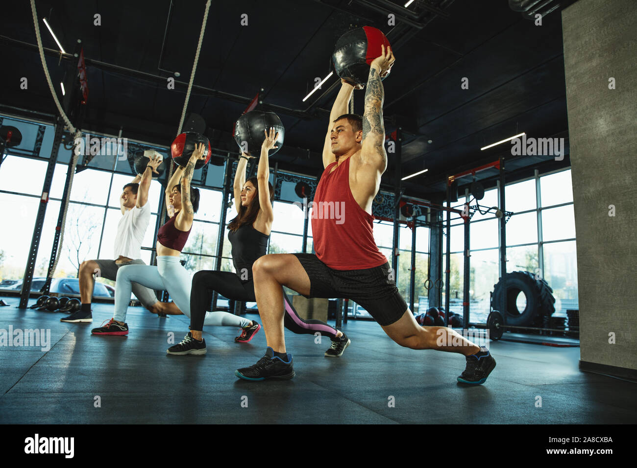 A group of muscular athletes doing workout at the gym. Gymnastics ...