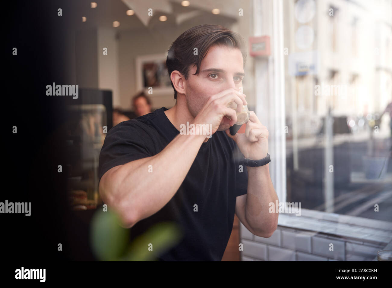 Young Man In Coffee Shop Talking On Mobile Phone Viewed Through Window ...