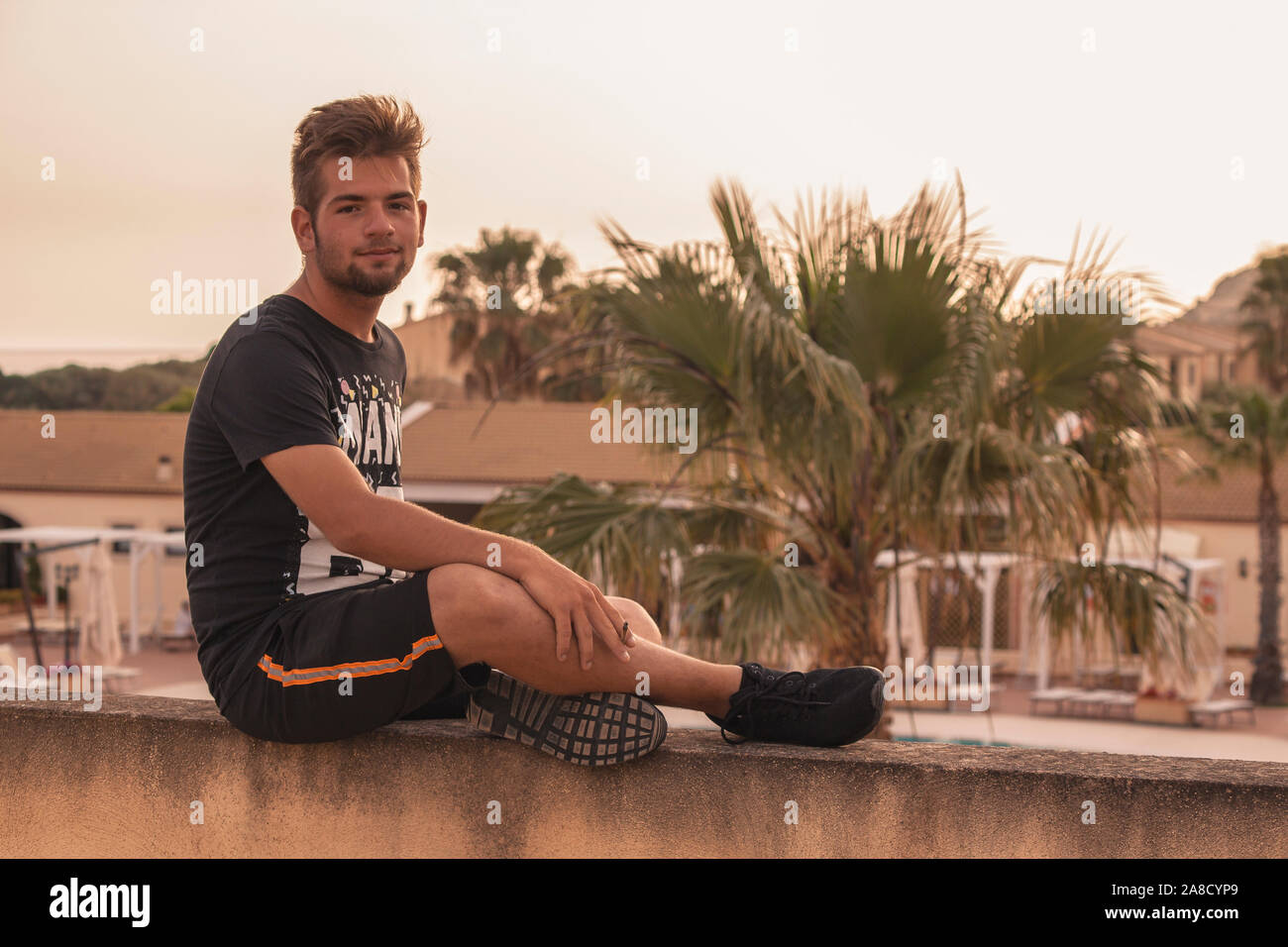 Guy sitting on a wall Stock Photo - Alamy