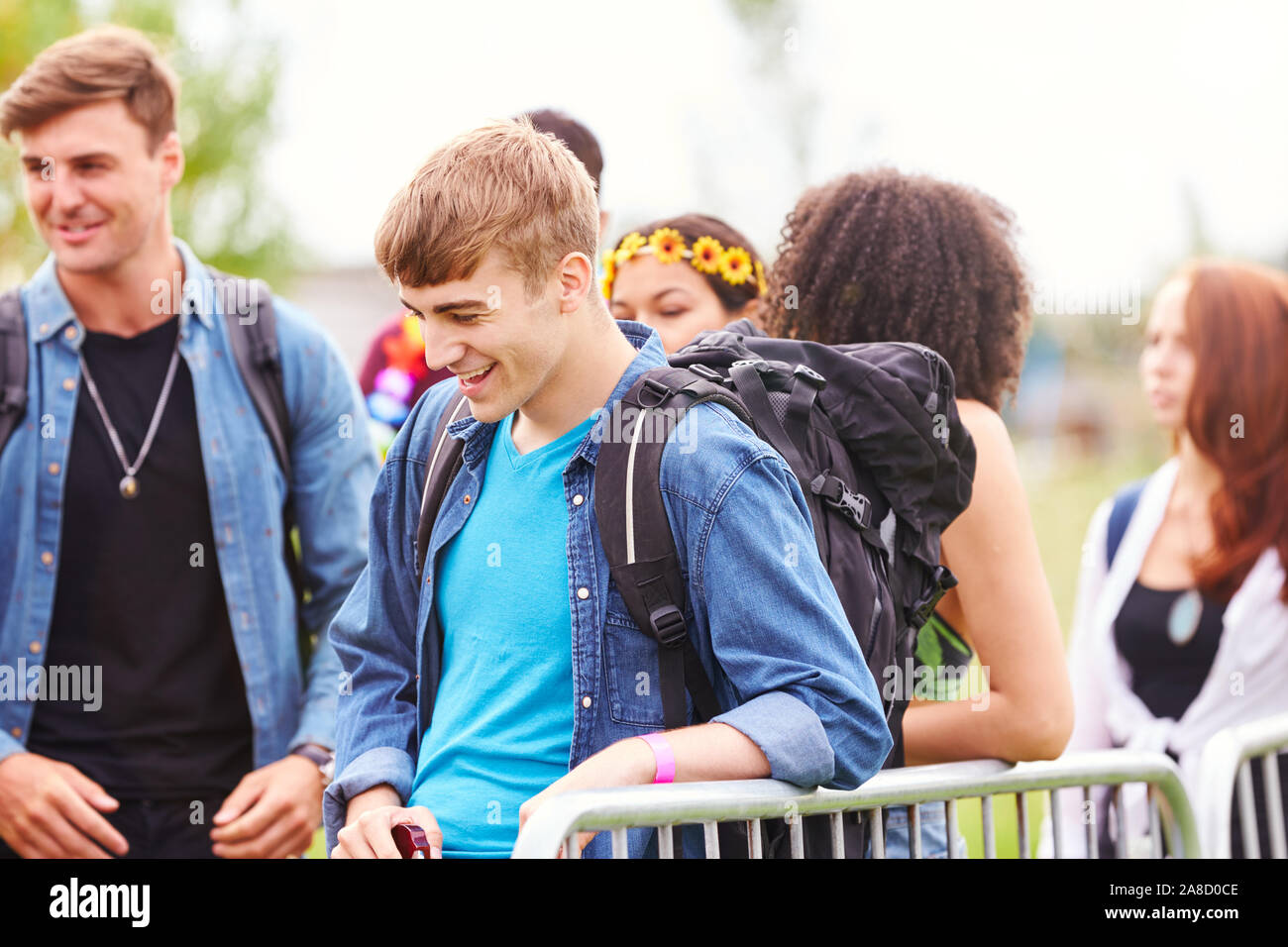 Group Of Young Friends Waiting Behind Barrier At Entrance To Music ...