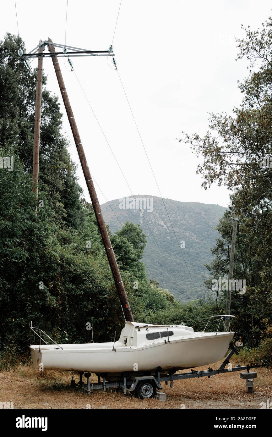 A boat and trailer on dry land in front of a telegraph pole resembling ...