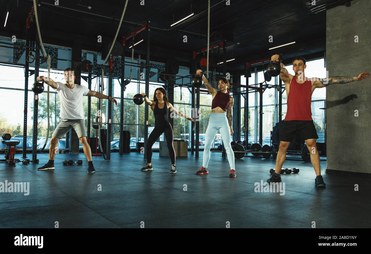 A group of muscular athletes doing workout at the gym. Gymnastics ...