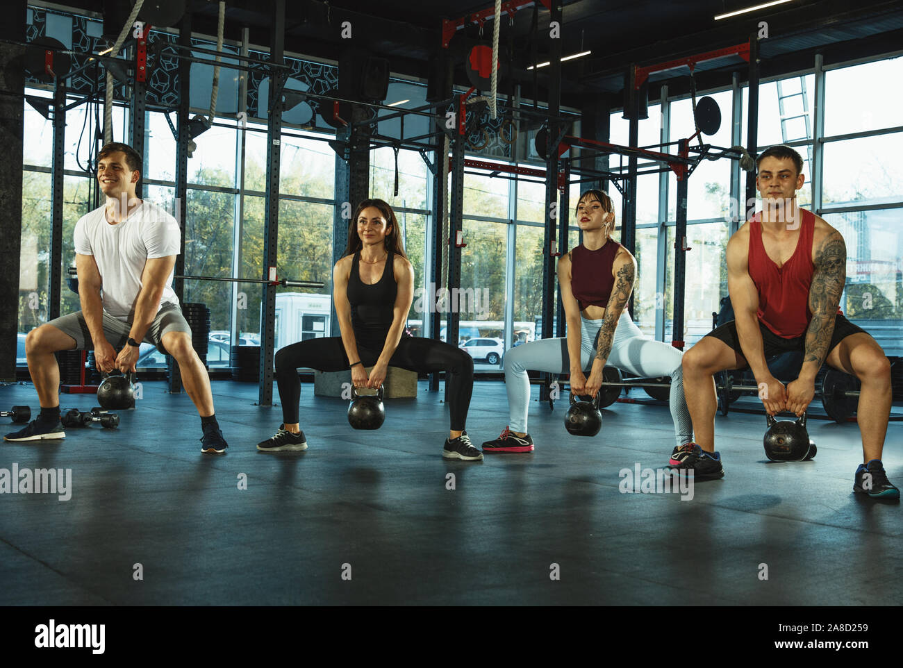 A group of muscular athletes doing workout at the gym. Gymnastics ...