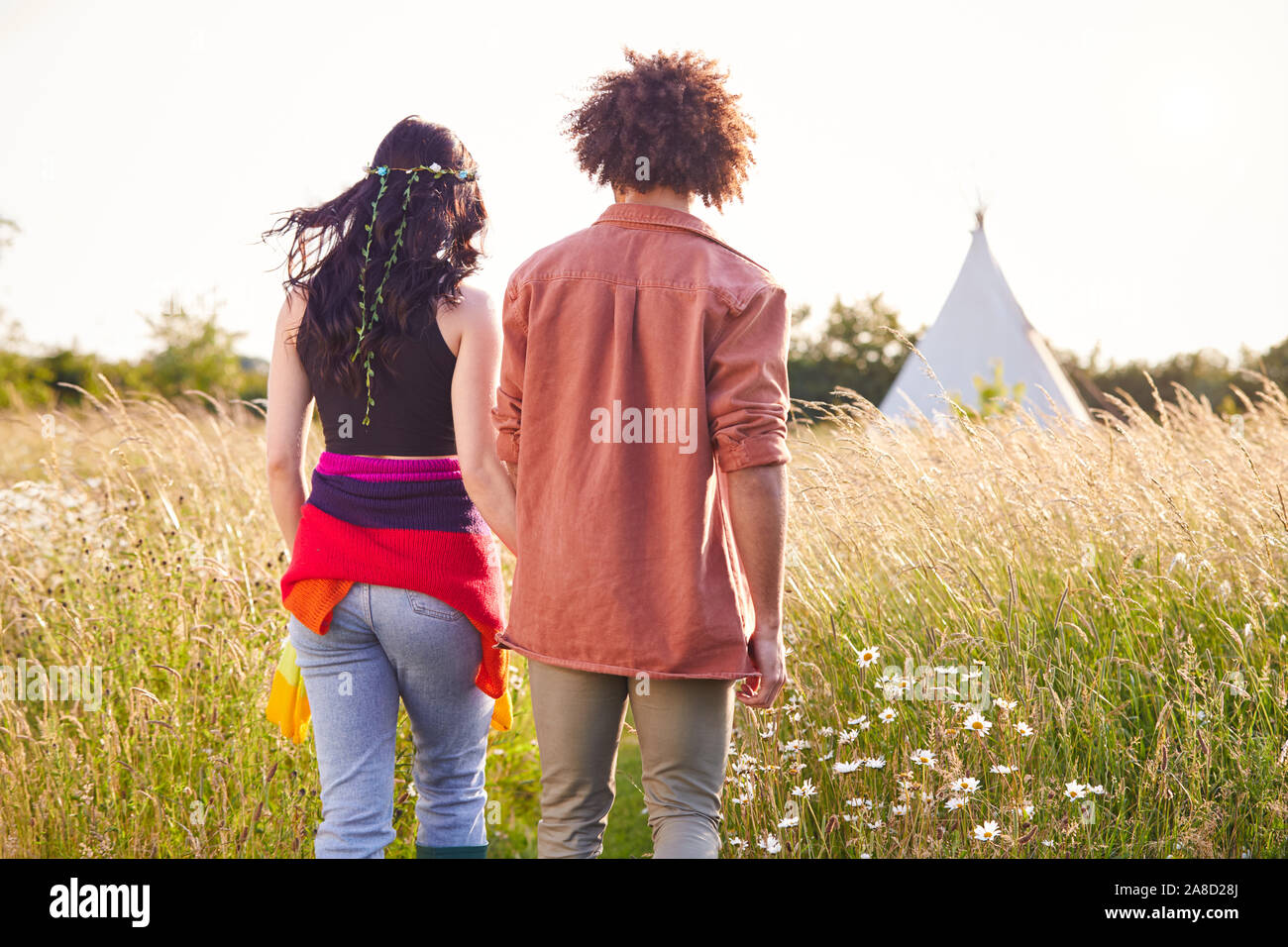 Young Romantic Couple Walking Through Field Towards Teepee On Summer ...