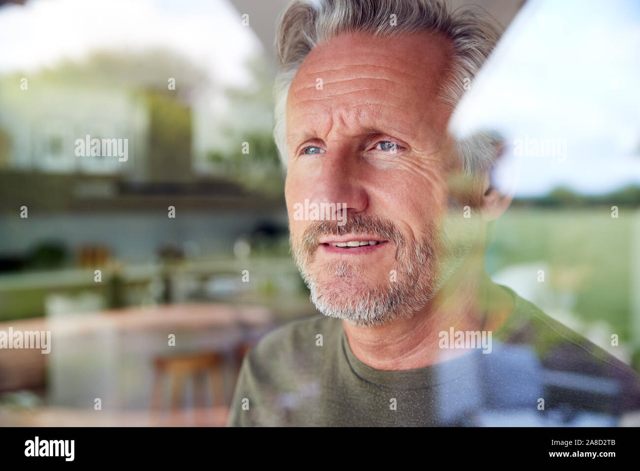 Senior Man Standing And Looking Out Of Kitchen Door Viewed Through ...